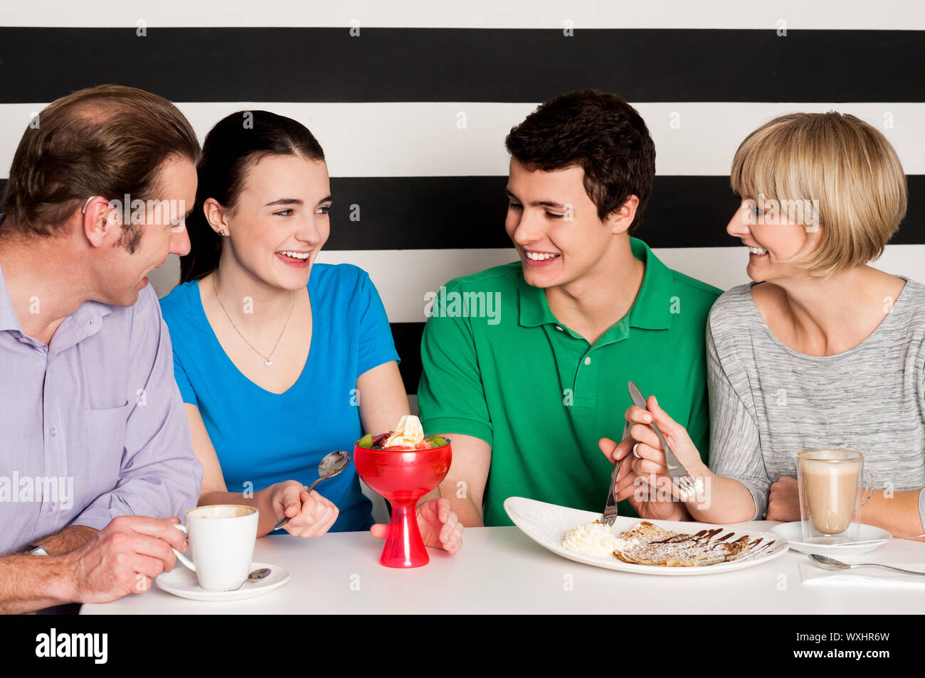 Cheerful family of four relishing delicious eatables and dessert Stock ...