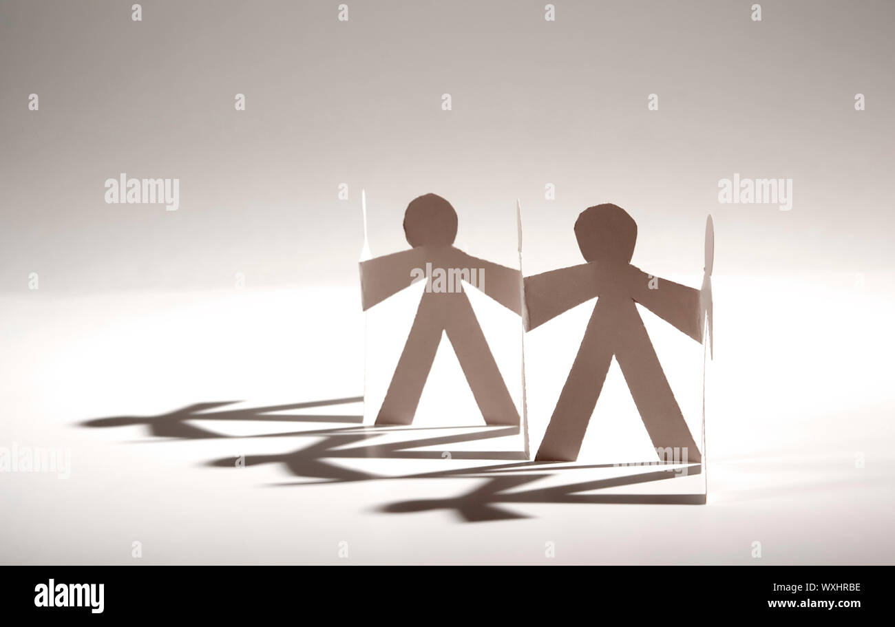 Line of cutout paper dolls throwing a shadow Stock Photo - Alamy