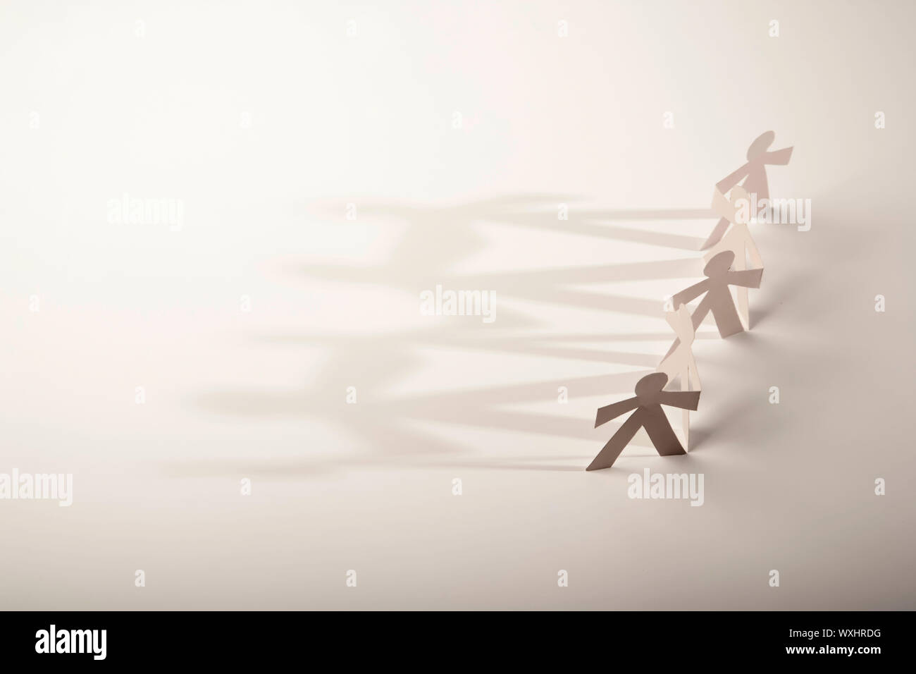 Line of cutout paper dolls throwing a shadow Stock Photo - Alamy