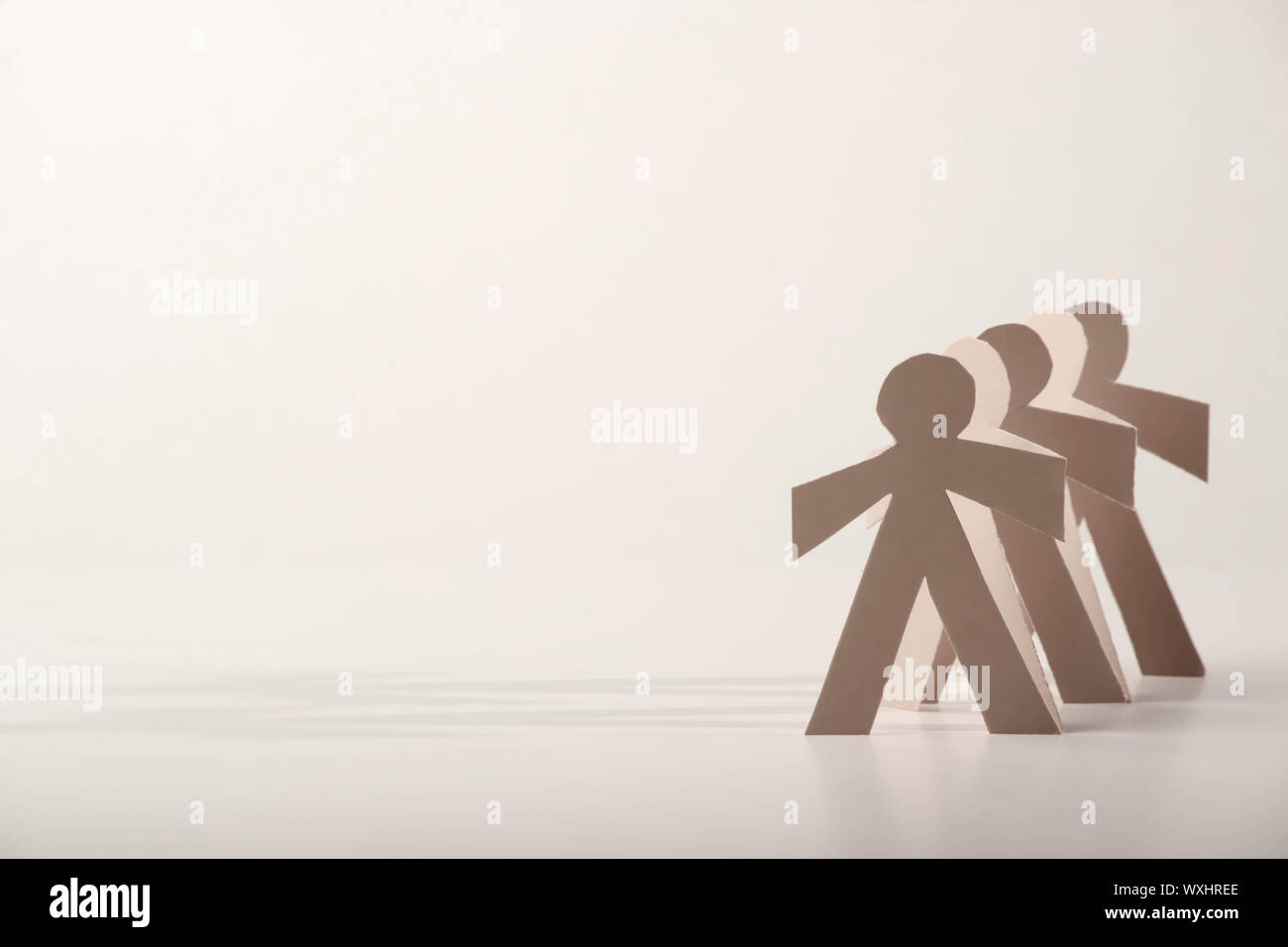 Line of cutout paper dolls throwing a shadow Stock Photo - Alamy