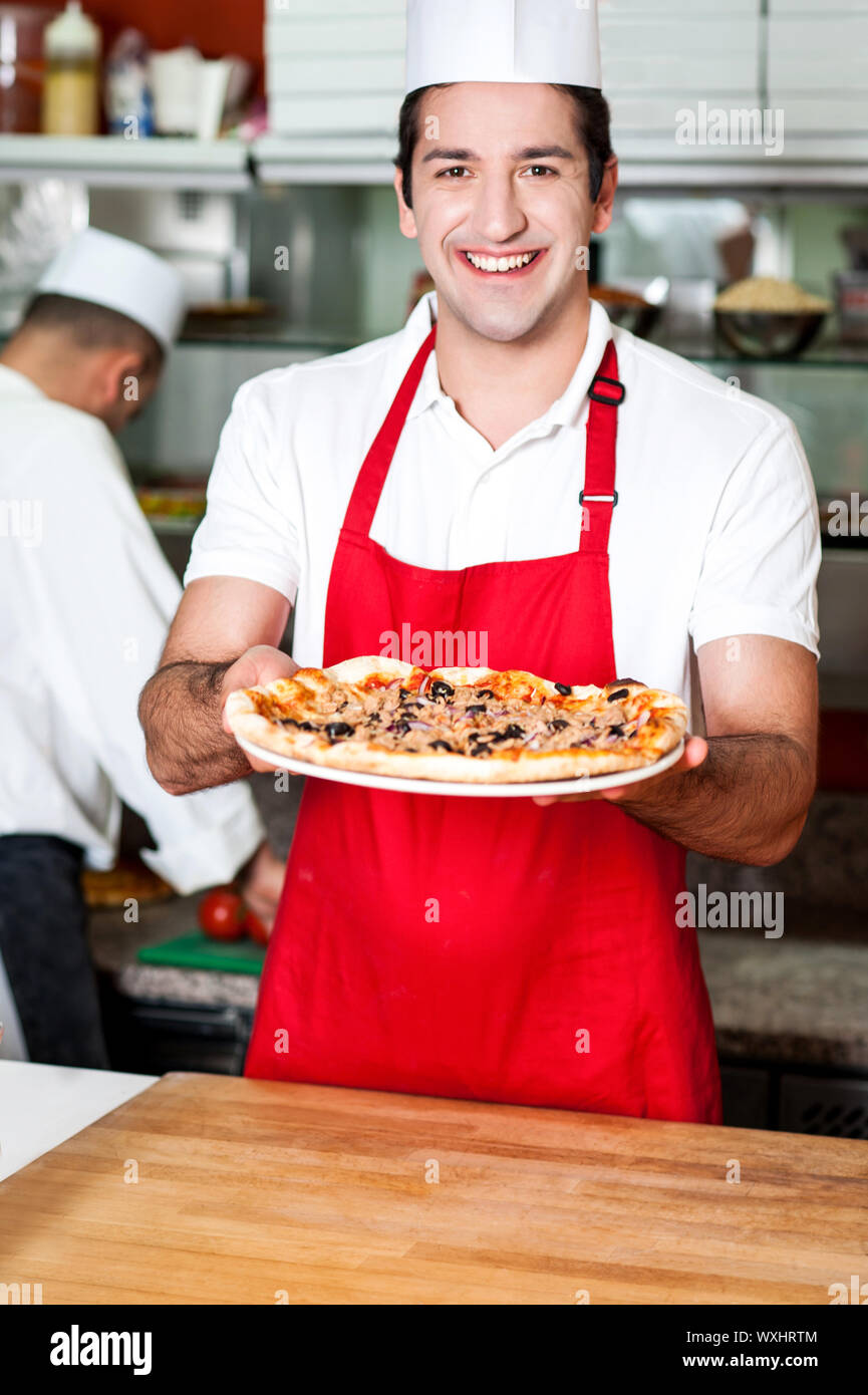 Young male chef handing over pizza Stock Photo - Alamy