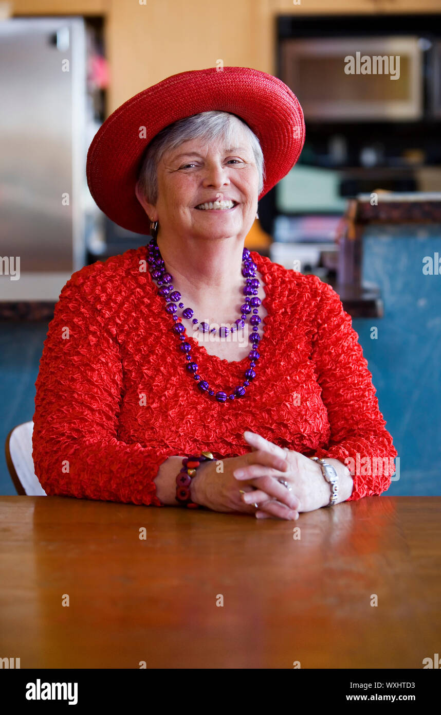 Friendly senior woman wearing a red hat Stock Photo - Alamy