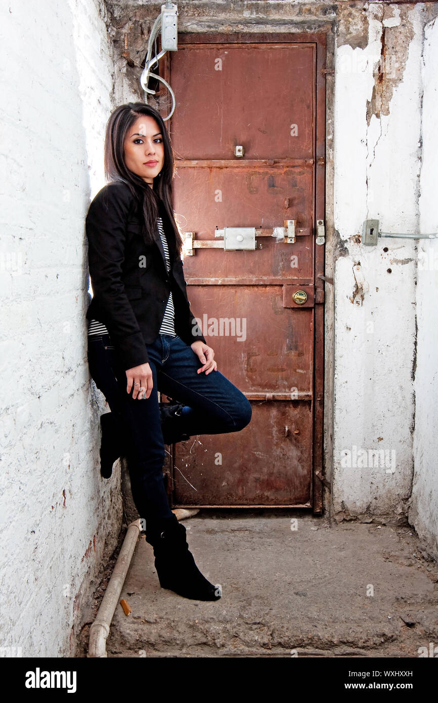 Beautiful Caucasian girl standing in basement in front of brown door ...