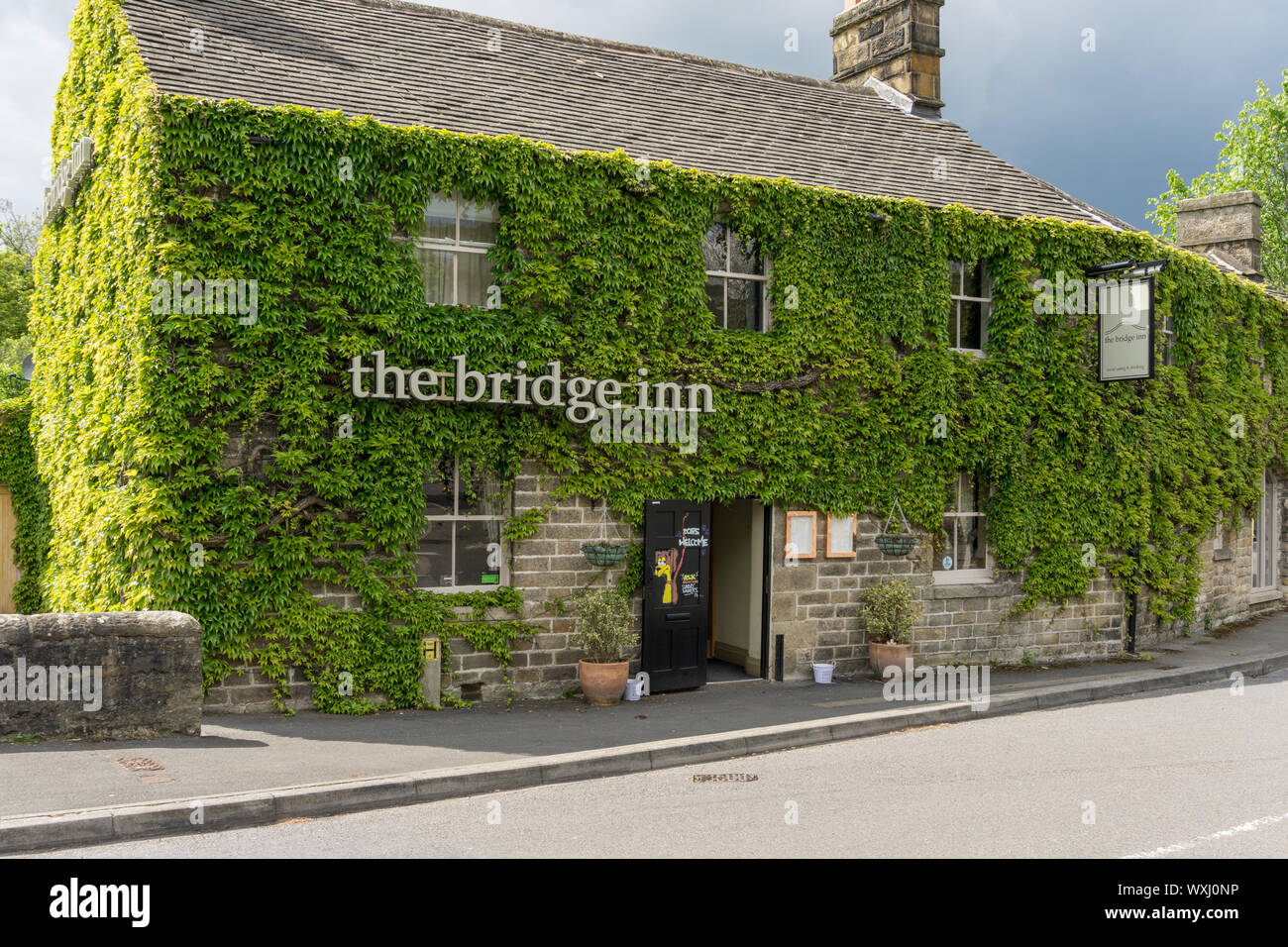 The pretty ivy clad exterior of the Bridge Inn in the village of Calver ...