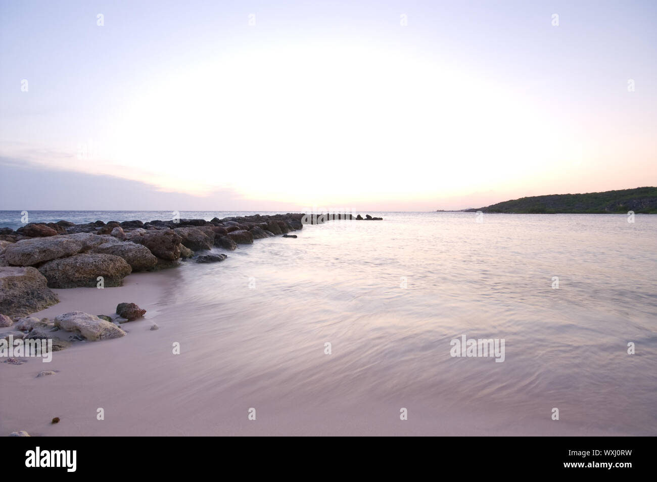 purple blue sea sunset with a rock wave breaker Stock Photo - Alamy