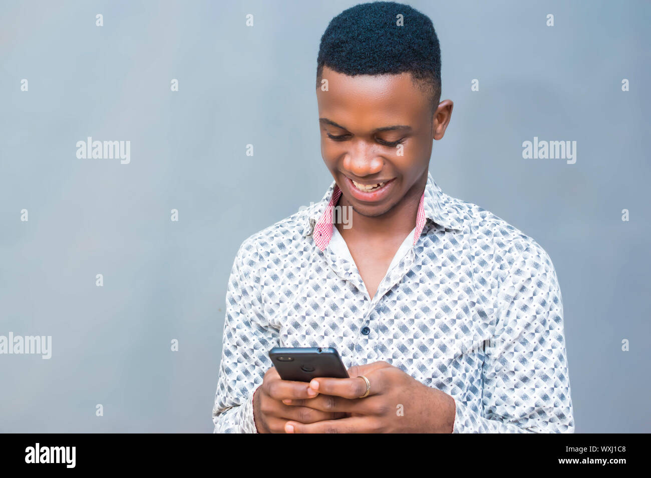 black african young hipster smiling using mobile phone, reading text ...