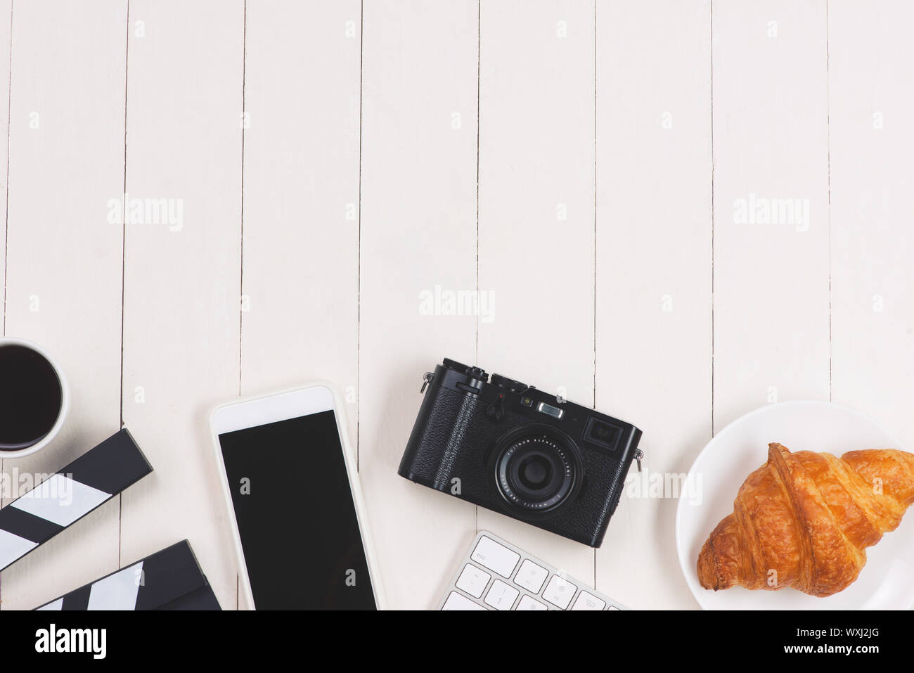 Film sign with smartphone, camera, cake, keyboard on wood background ...