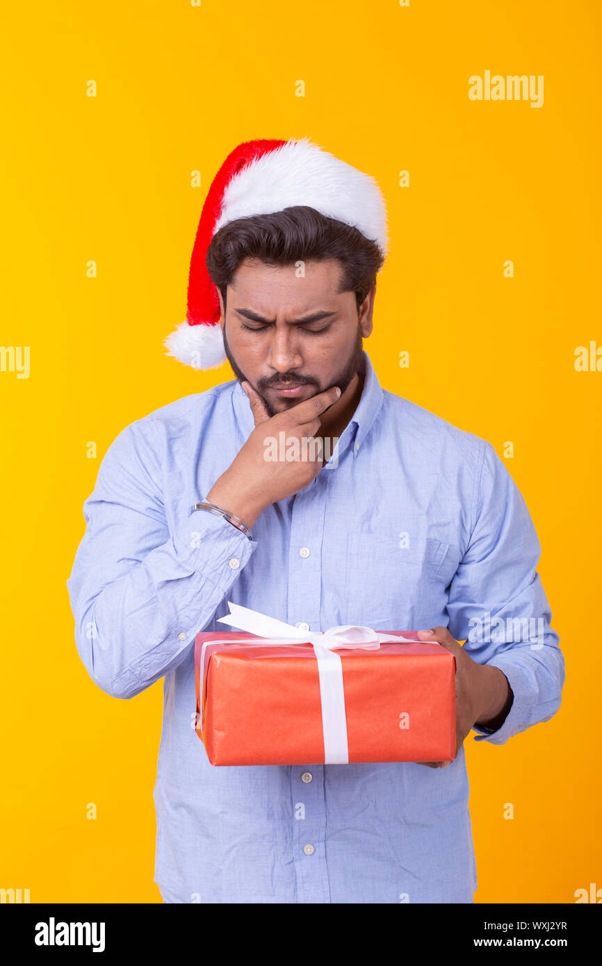 Positive young indian man Santa Claus with gifts and Christmas tree ...