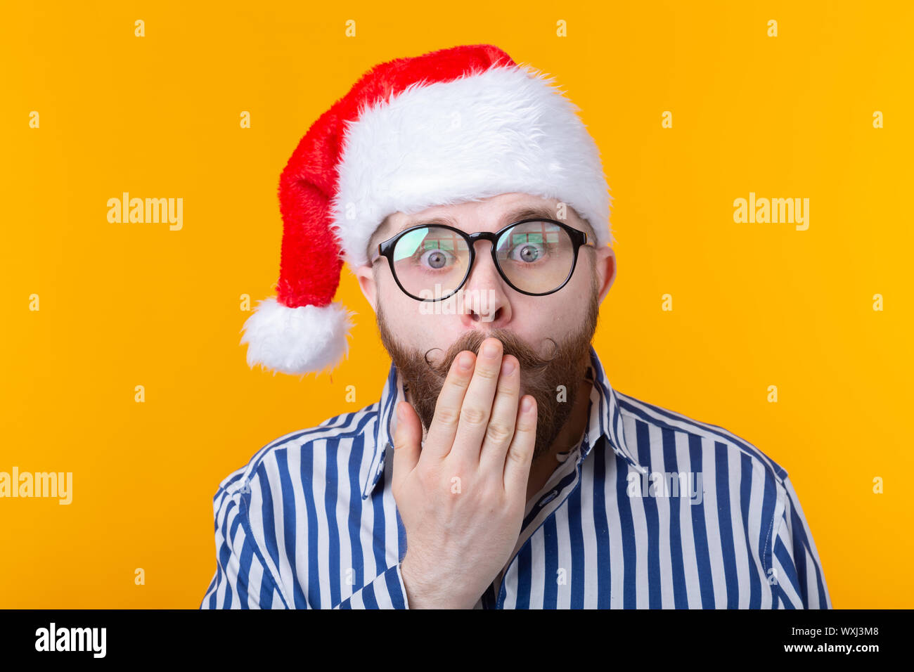 Surprised young man Santa Claus startledly closes his mouth while ...