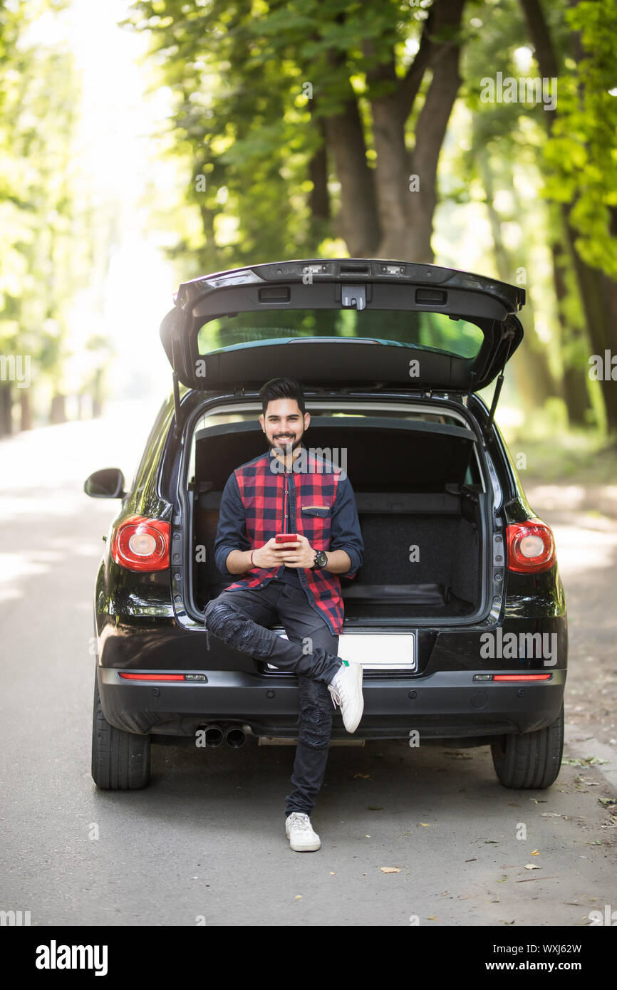 Young indian man use her phone sitting in the trunk on the road Stock ...