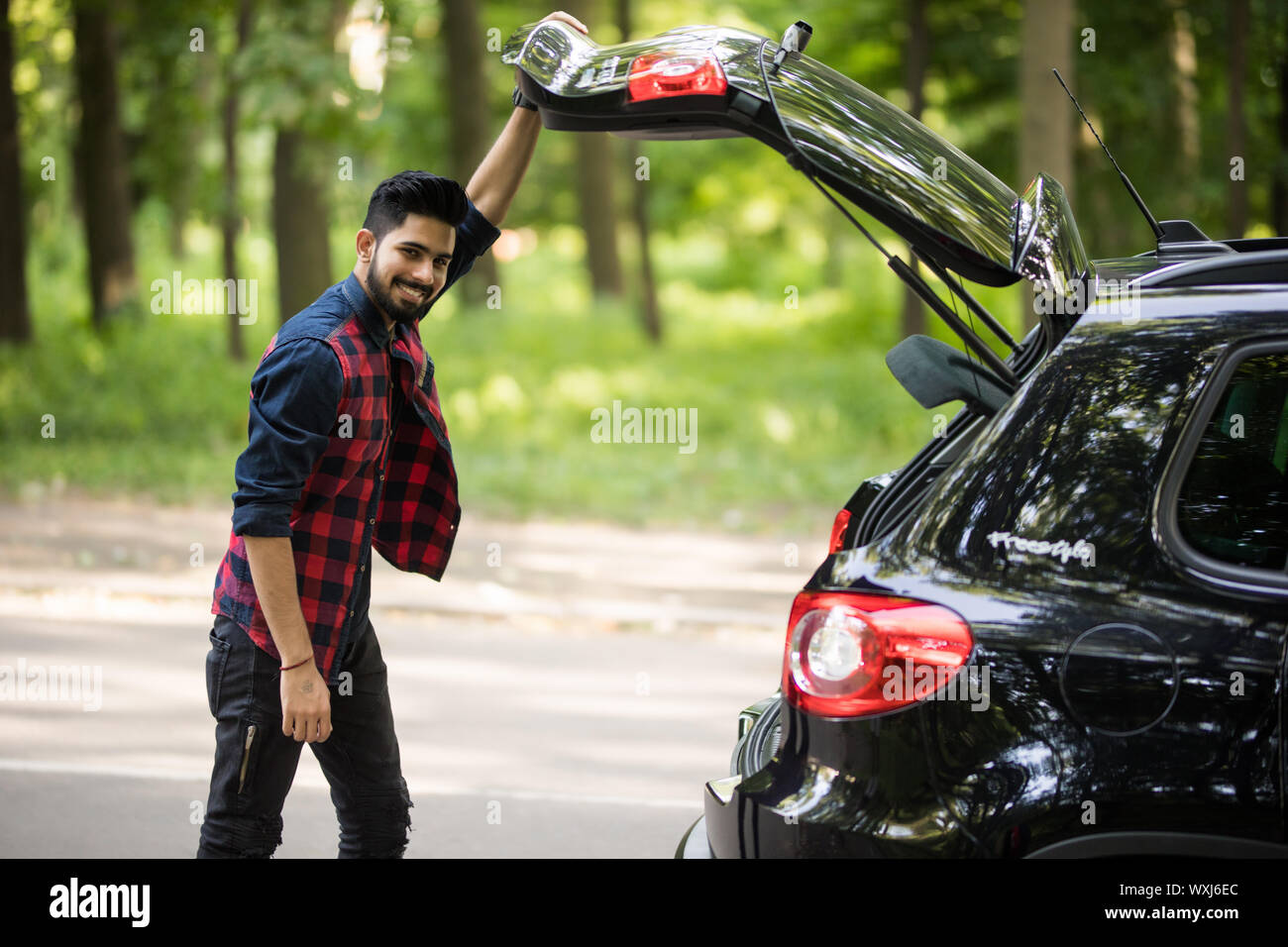 Young man open the trunk on the street road Stock Photo - Alamy