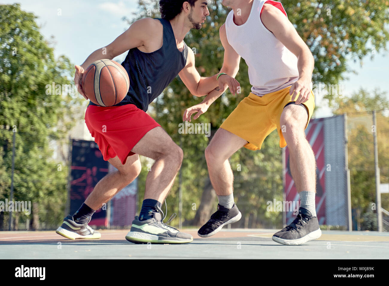 Image of two sporty men playing basketball on playground on summer day ...