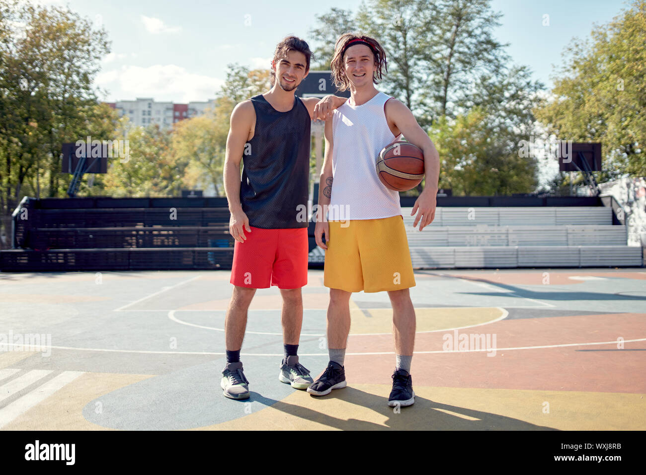 Full-length photo of two athletes with basketball on playground on ...