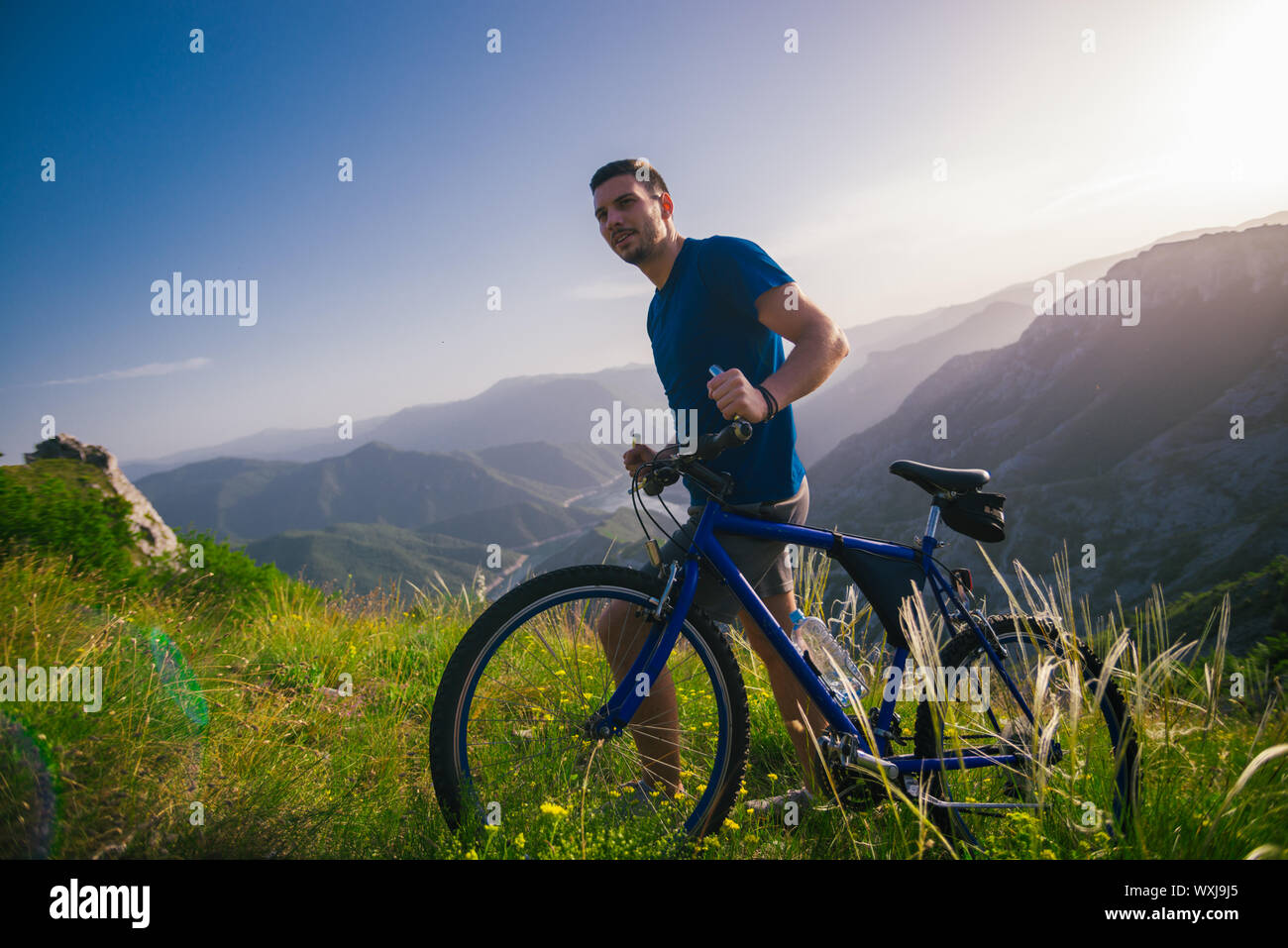 Perspective of a fit mountain biker pushing his bike uphill with ...