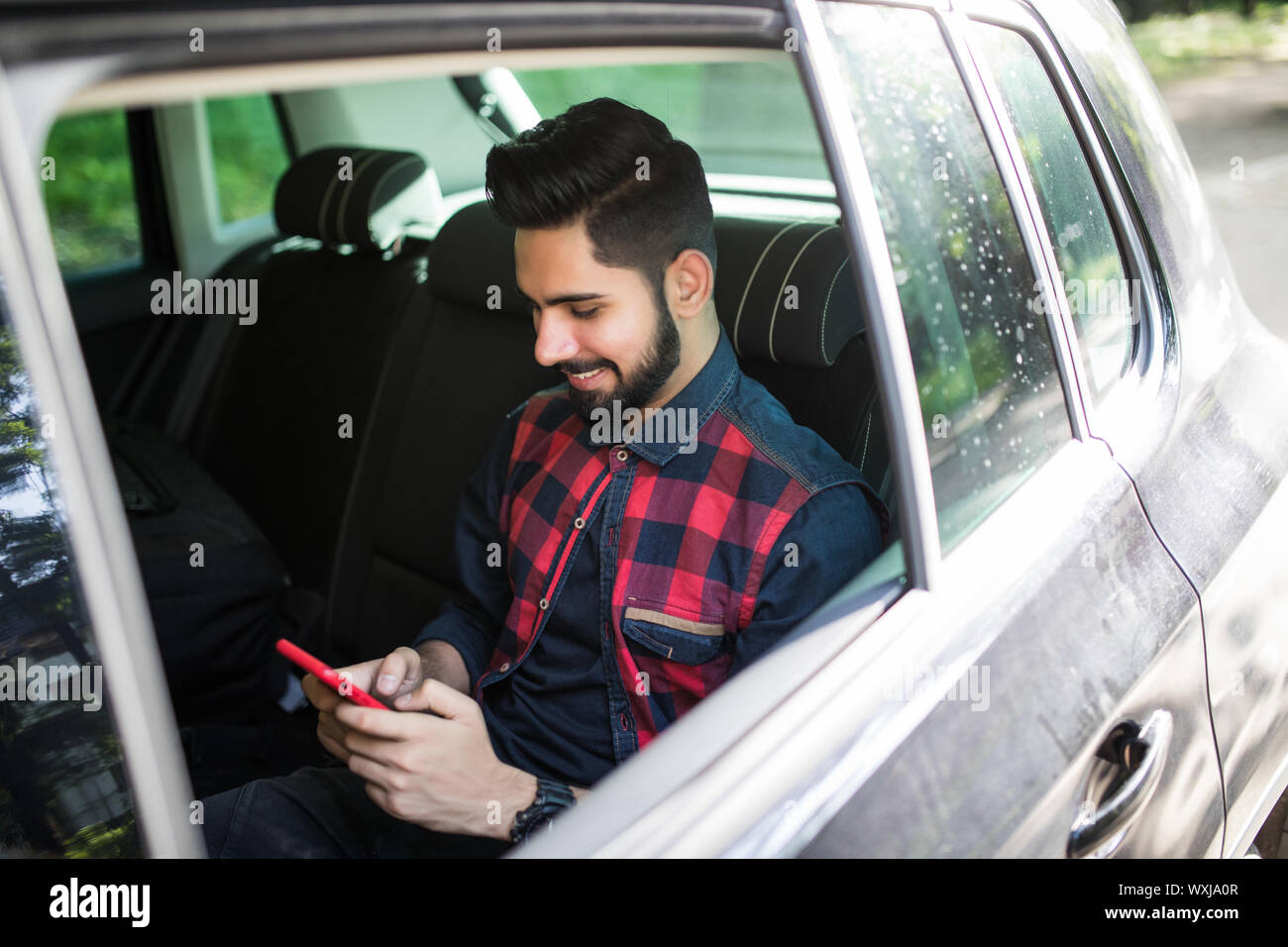indian man typing on mobile phone in rear of the car Stock Photo - Alamy