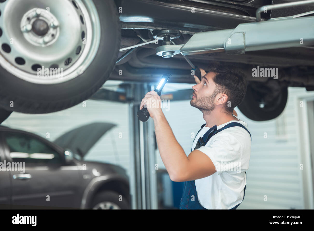 young handsome mechanic working in car service department scanning the ...