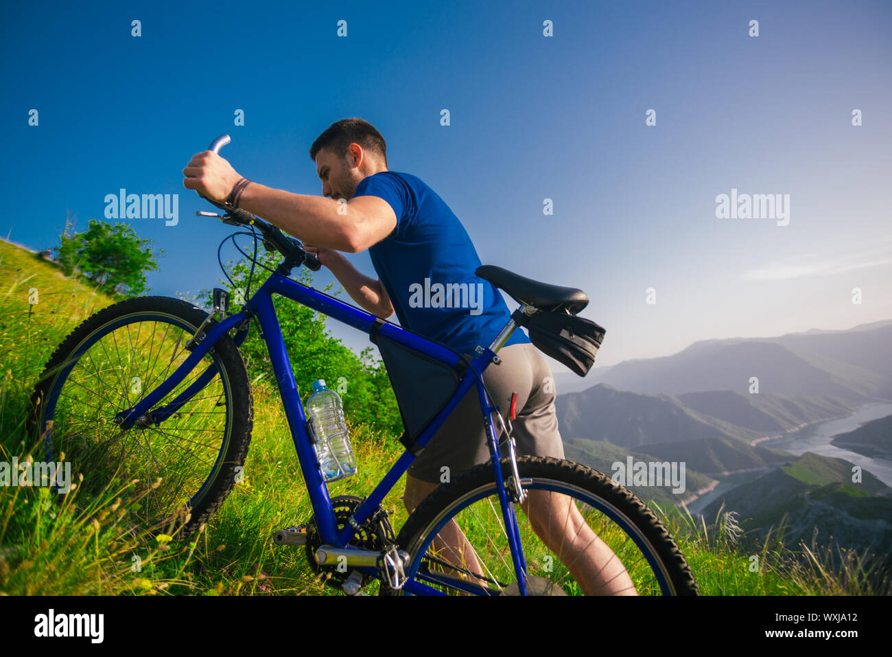 Perspective of a fit mountain biker pushing his bike uphill with ...
