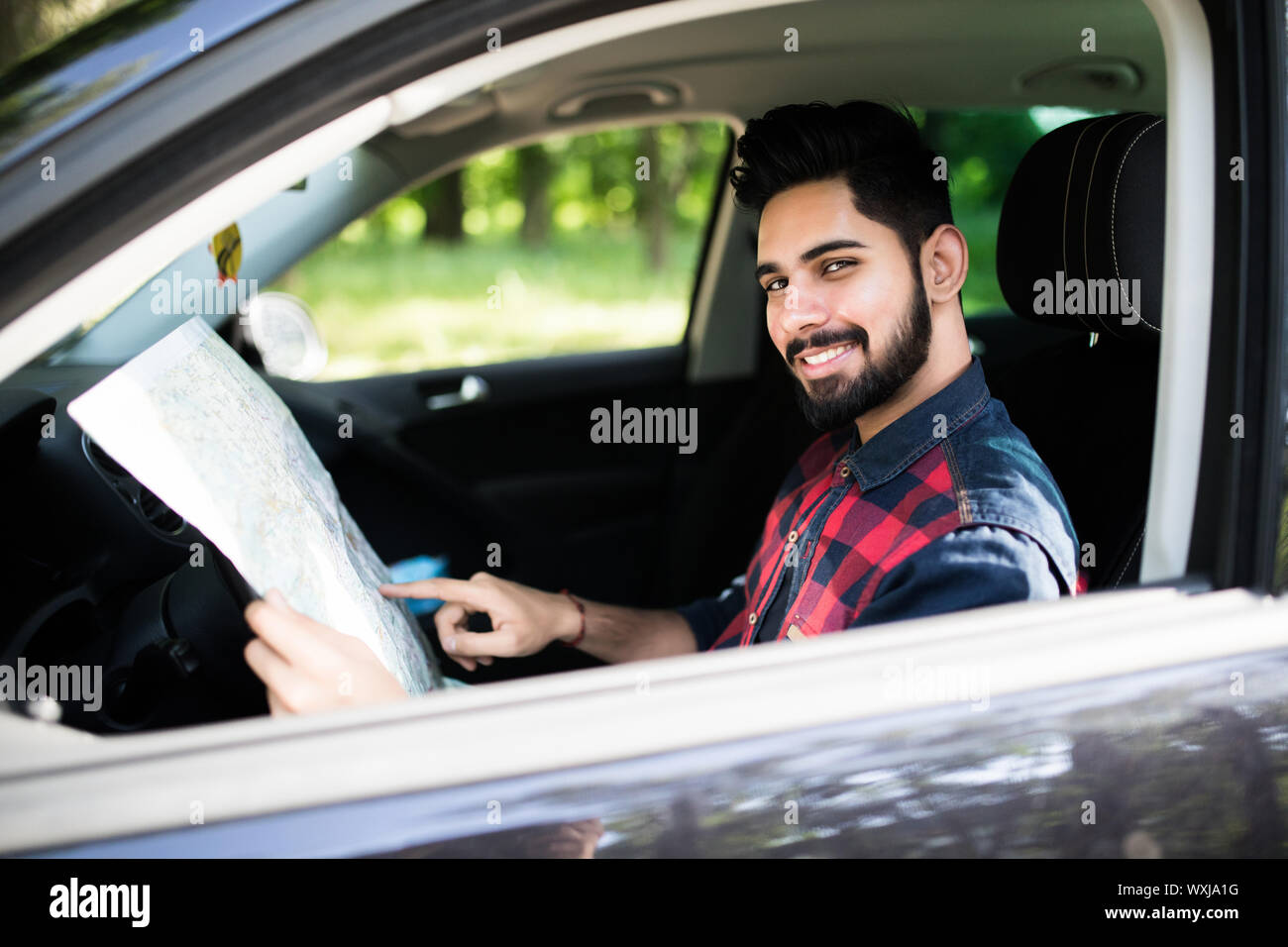 Man siting in the car and looking at road map. Traveler searching right ...