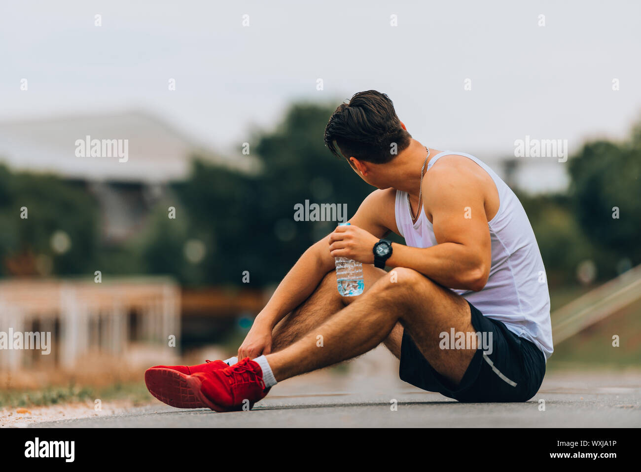 Good looking young man looking tired from running outdoors and taking a ...