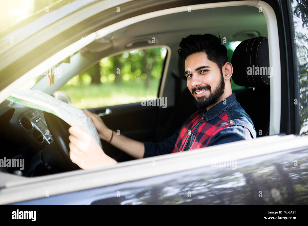 Man siting in the car and looking at road map. Traveler searching right ...