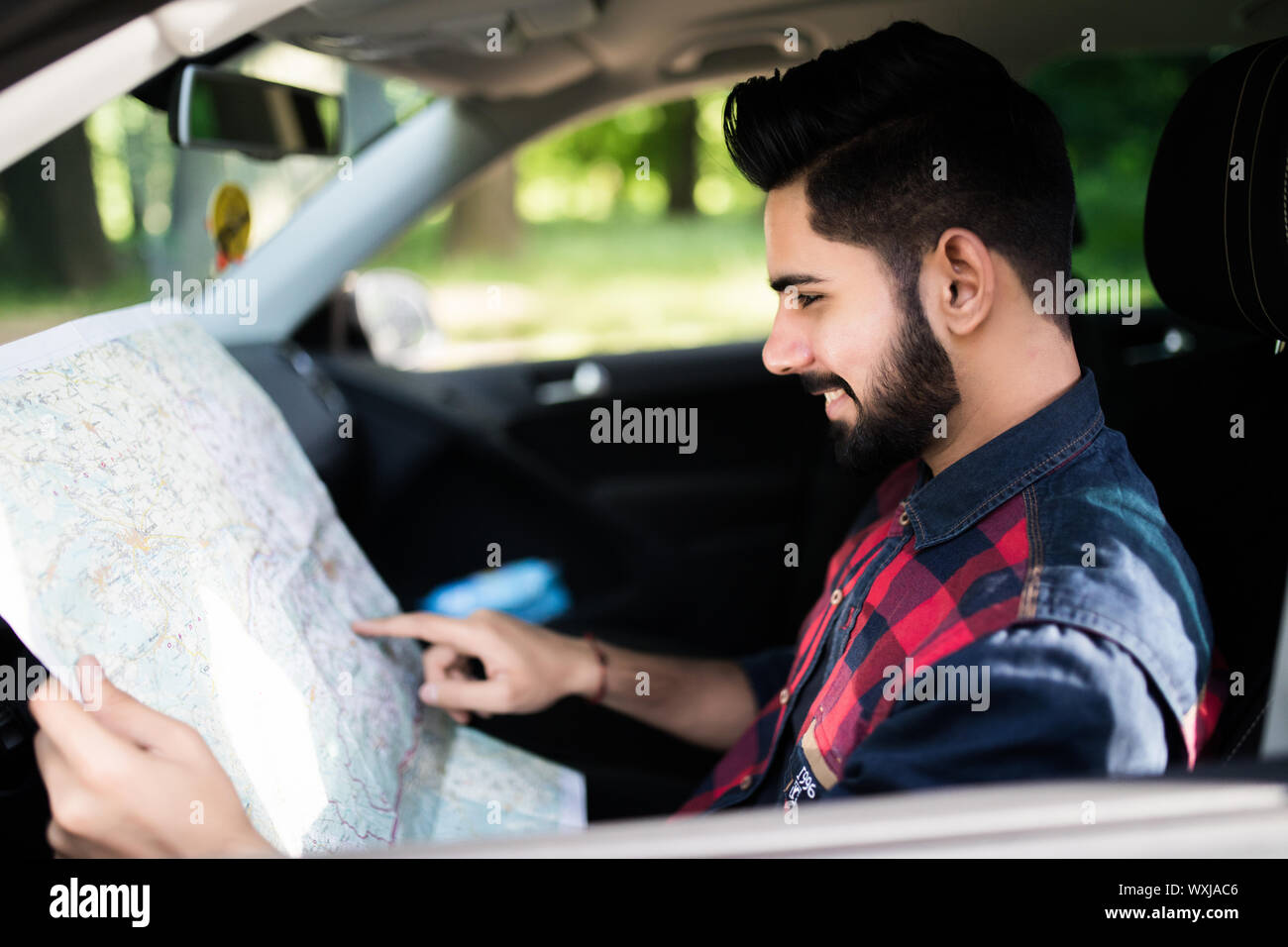 Man siting in the car and looking at road map. Traveler searching right ...