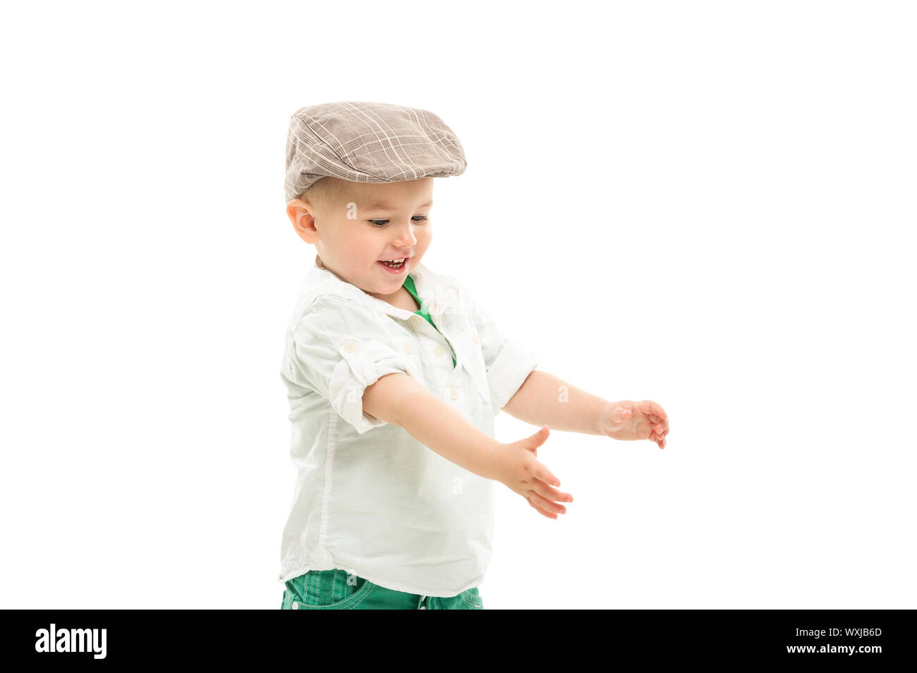 Laughing youngster wearing a cute cloth cap holding out his hands as ...