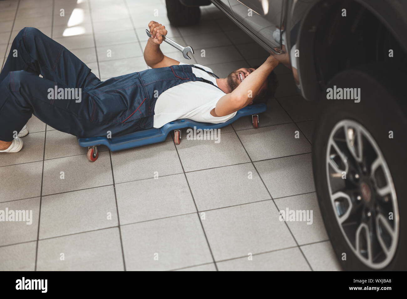young handsome mechanic working in car service department fixing ...