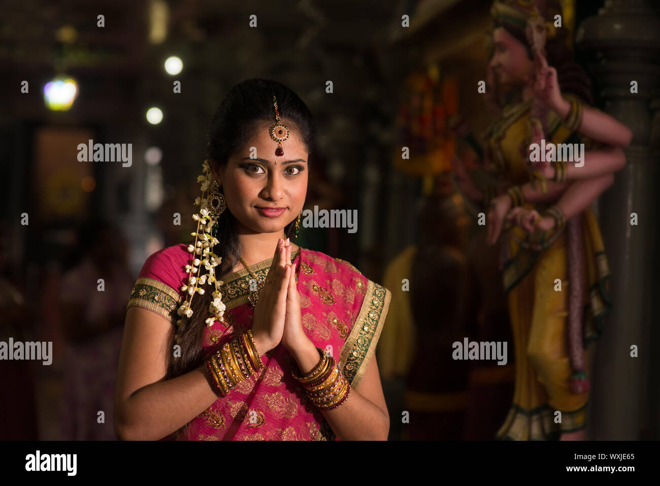 Young Indian girl in traditional sari dress praying in a hindu temple ...