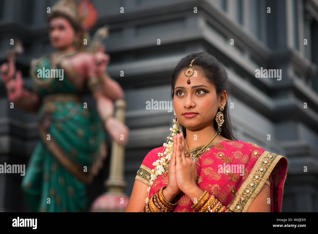 Beautiful young Indian woman in traditional sari dress praying in a ...