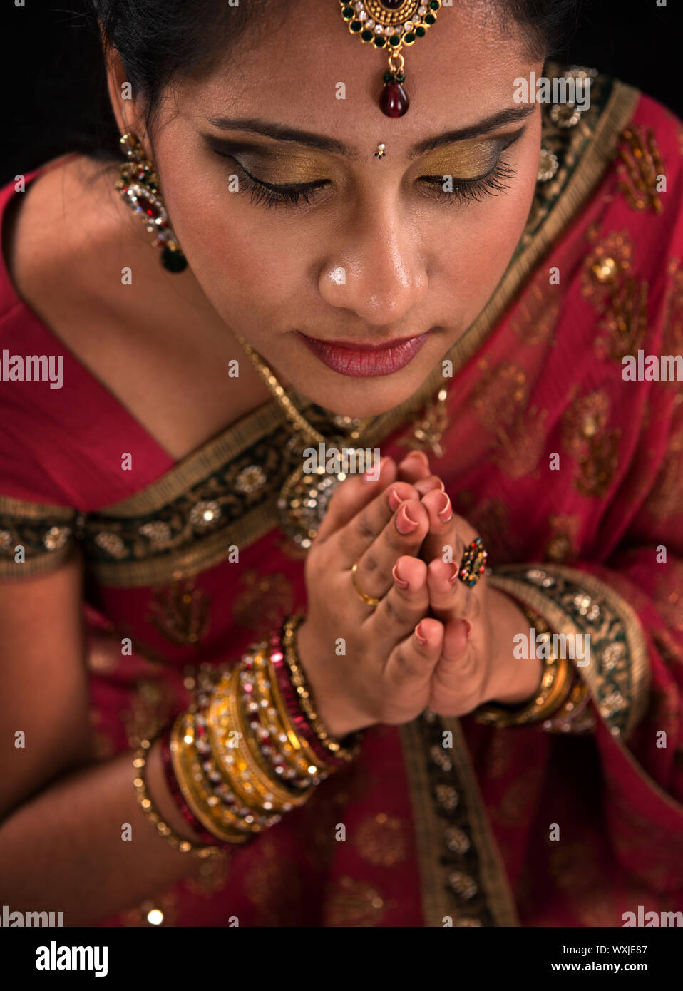 Close up portrait of beautiful young Indian woman prayer in traditional ...