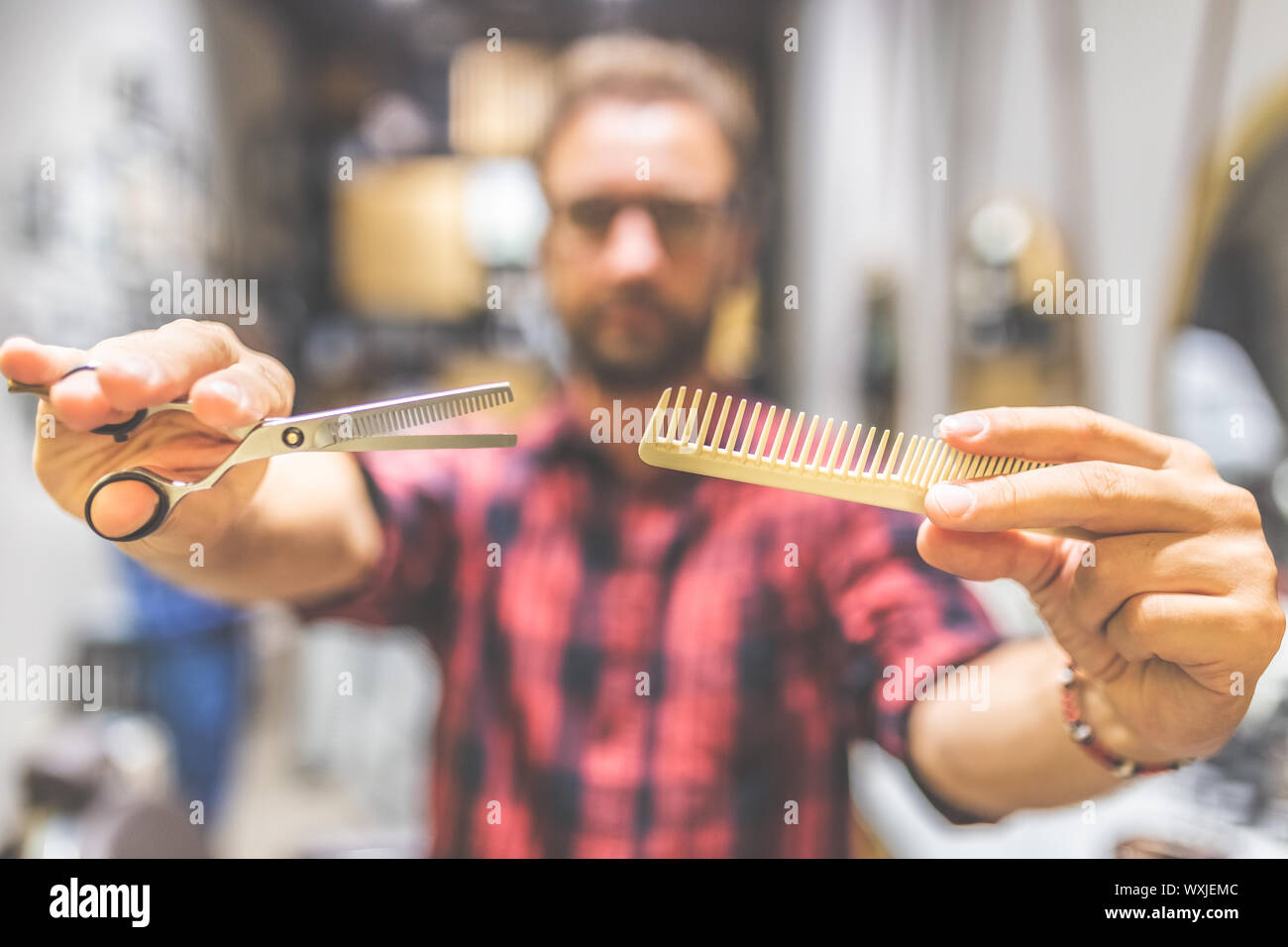 Modern barber holding comb and scissors at barbershop Stock Photo - Alamy