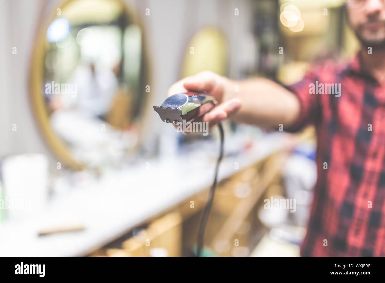 Modern barber holding hair clipper at barbershop Stock Photo - Alamy