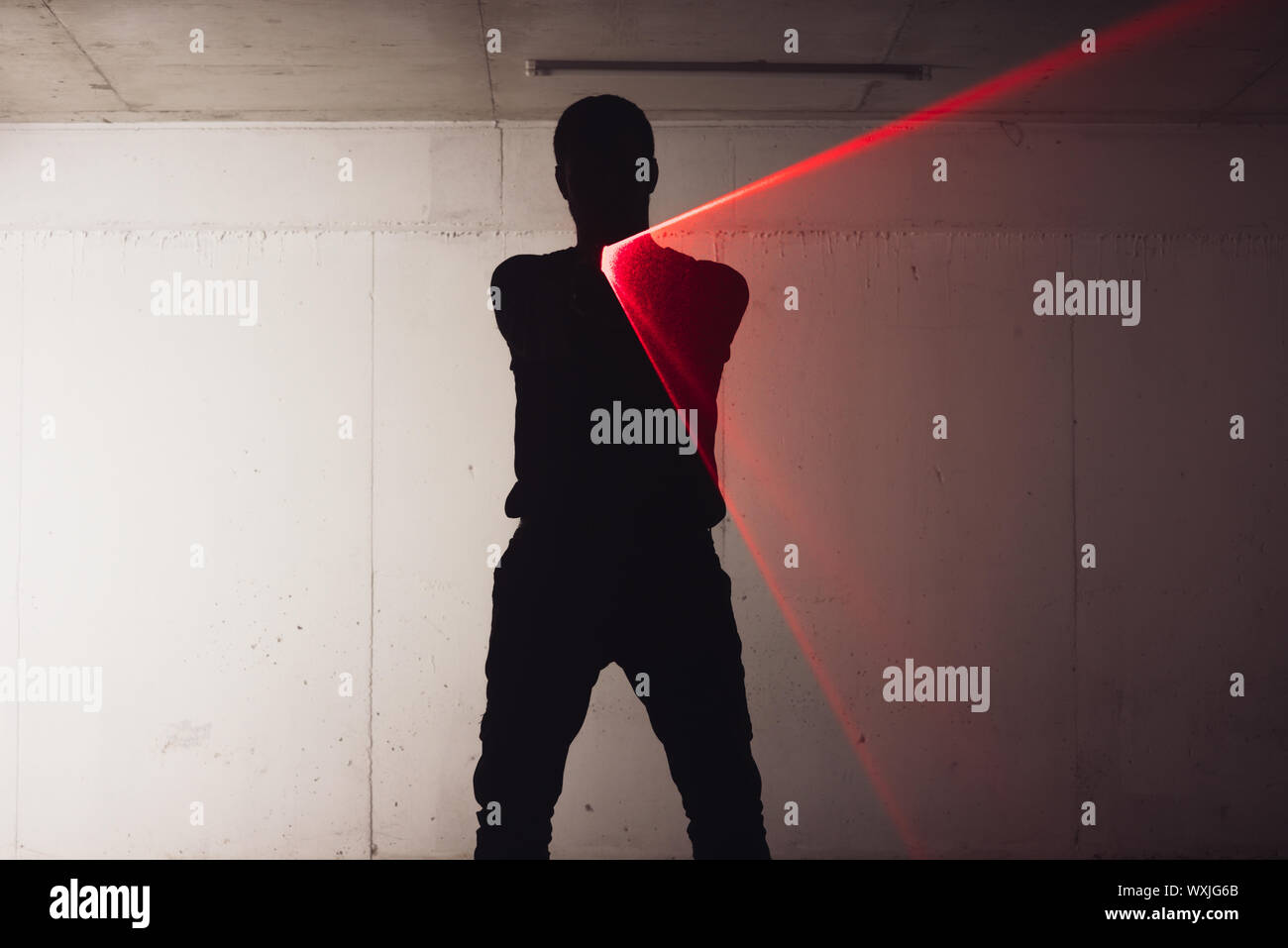 silhouette of an armed man holding his gun and pointing with his laser ...