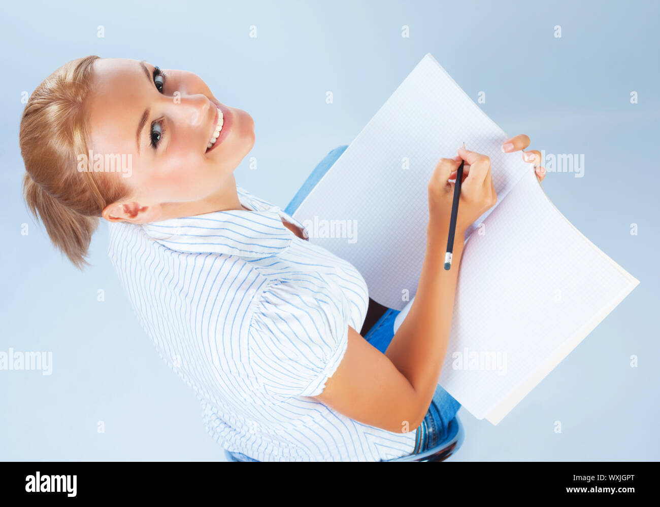 Portrait of cute student girl passing exam, isolated on blue background ...