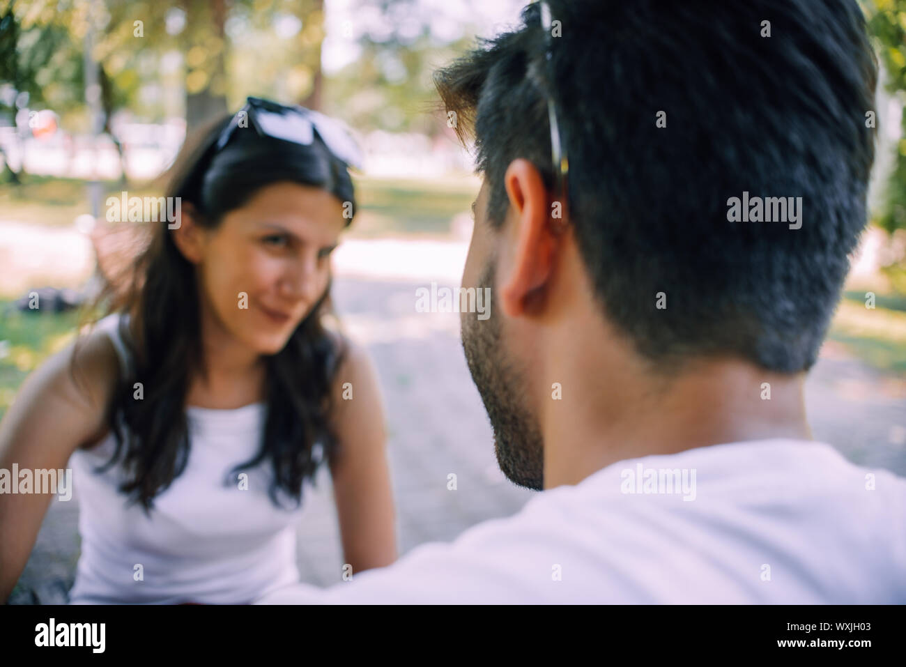 Back view of beautiful love couple sitting outdoors on a bench looking ...