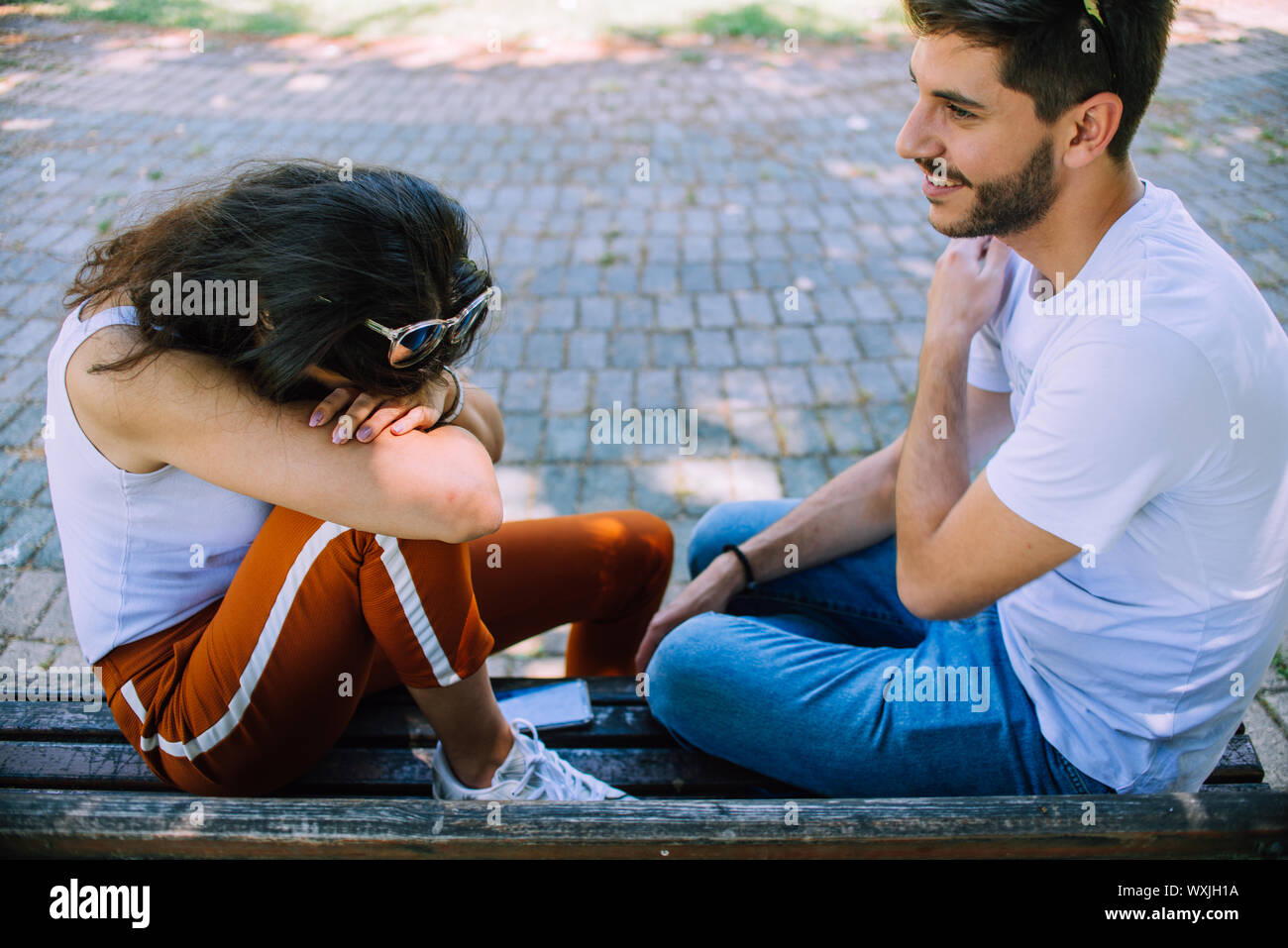 Happy casual couple talking looking each other sitting in a park with a ...