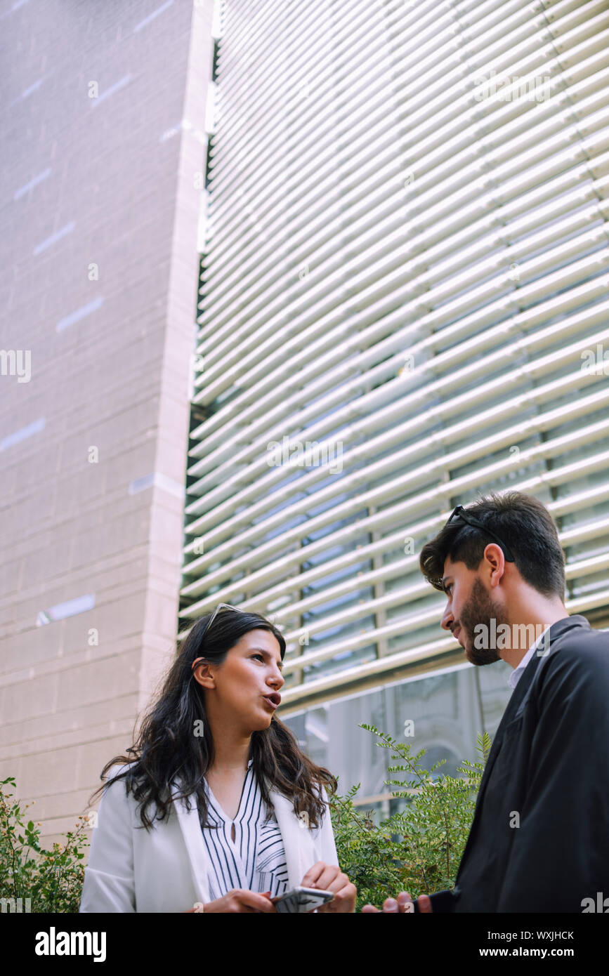 Happy Caucasian business colleagues walking outside office & talking to ...