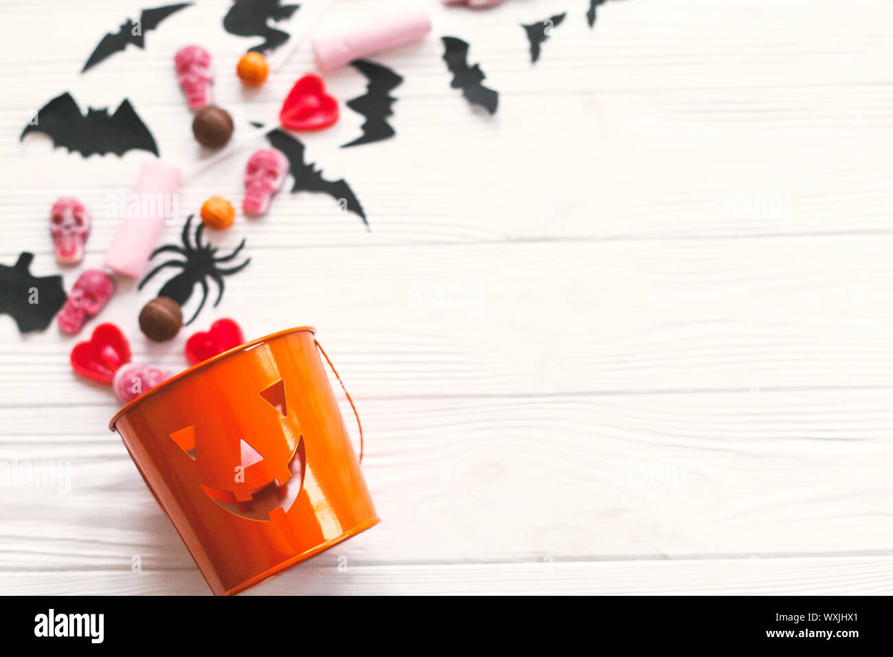 Trick or treat. Halloween candy spilled from jack o lantern bucket with ...