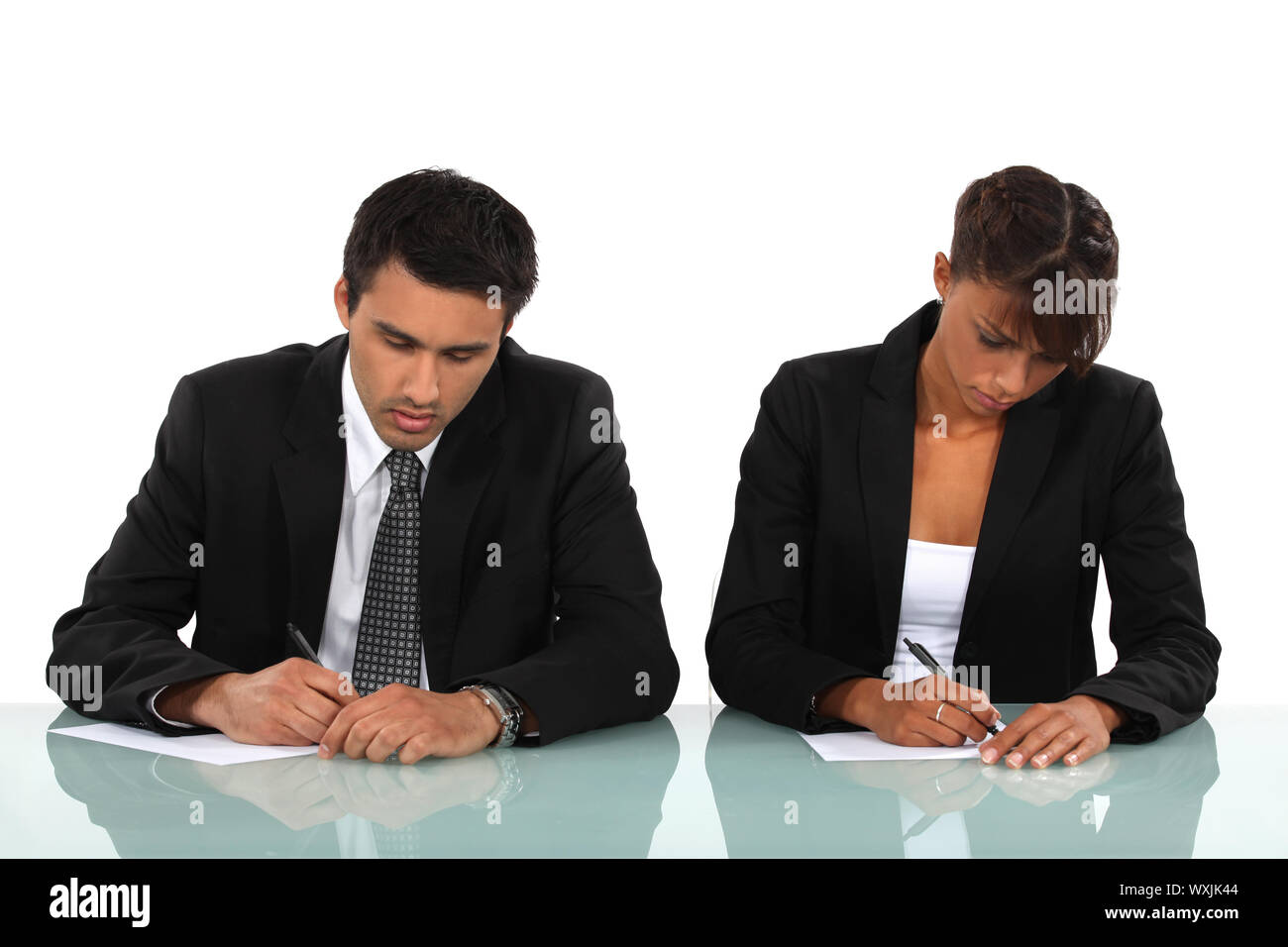 Two business people writing at a desk Stock Photo - Alamy