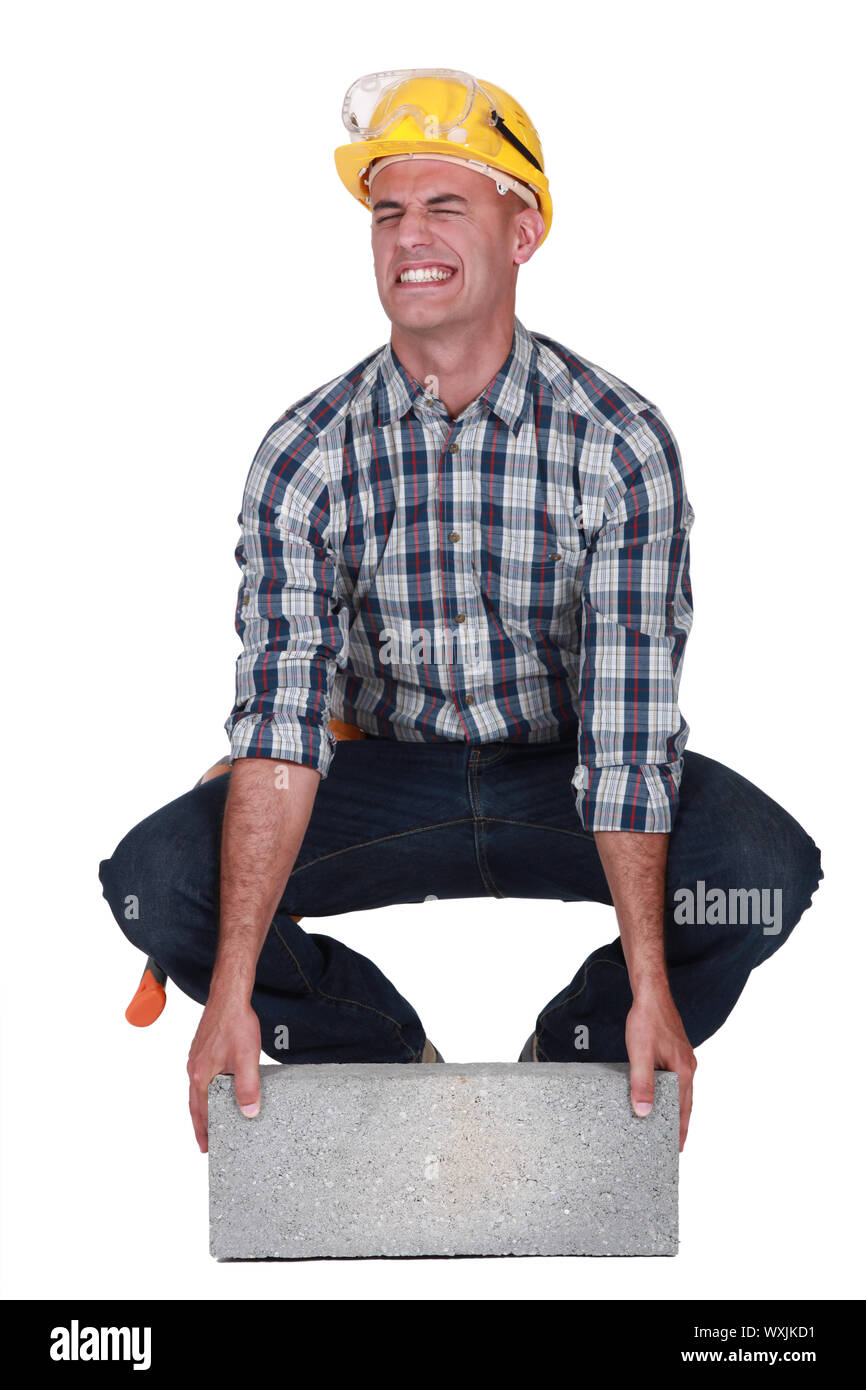 Construction worker lifting block Stock Photo - Alamy