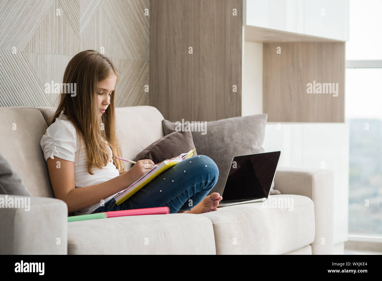 Focused school girl study at couch with computer. Young female student ...