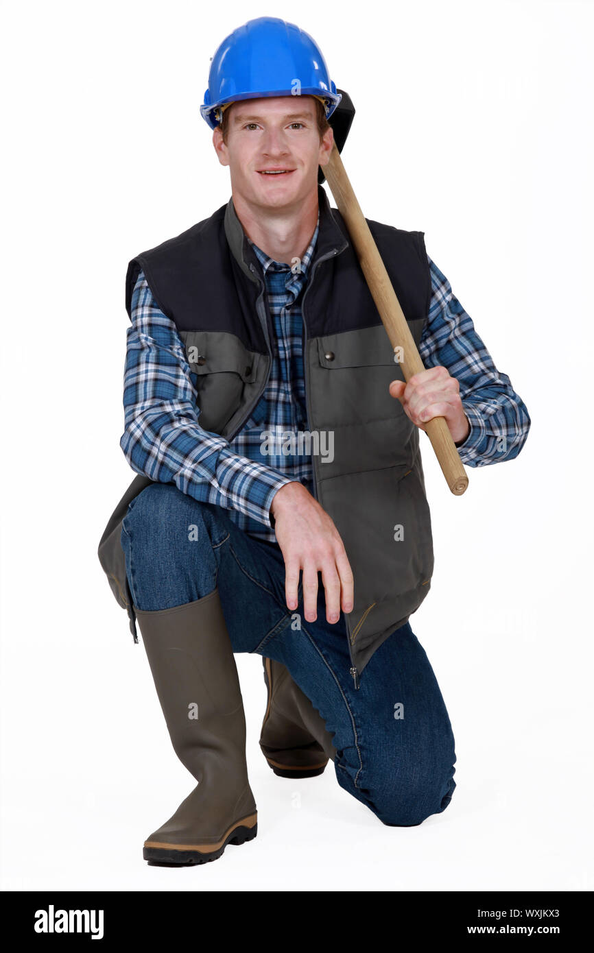 Worker kneeling with sledge-hammer over shoulder Stock Photo - Alamy