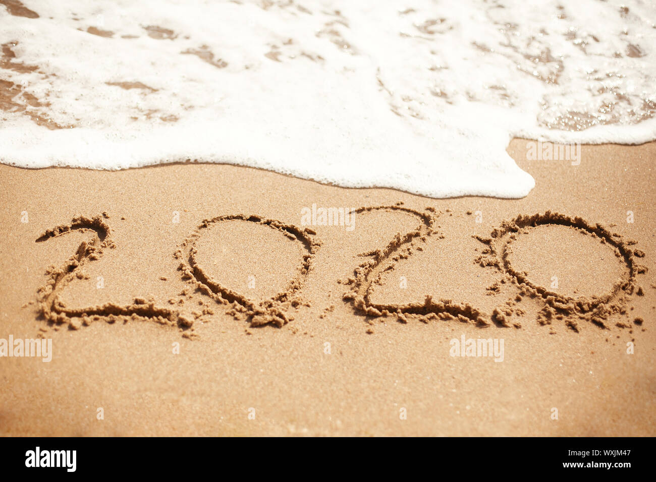 Happy New Year 2020, handwritten on sandy beach. 2020 numbers ...