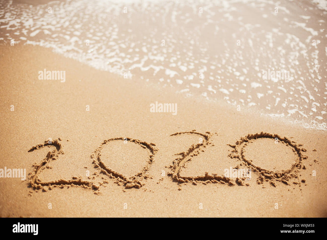 Happy New Year 2020, handwritten on sandy beach. 2020 numbers ...