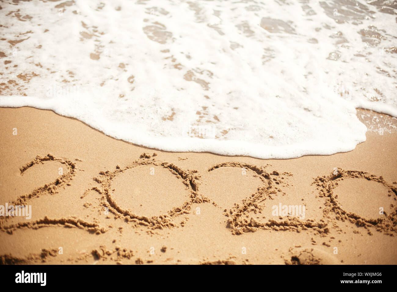 Happy New Year 2020, handwritten on sandy beach. 2020 numbers ...