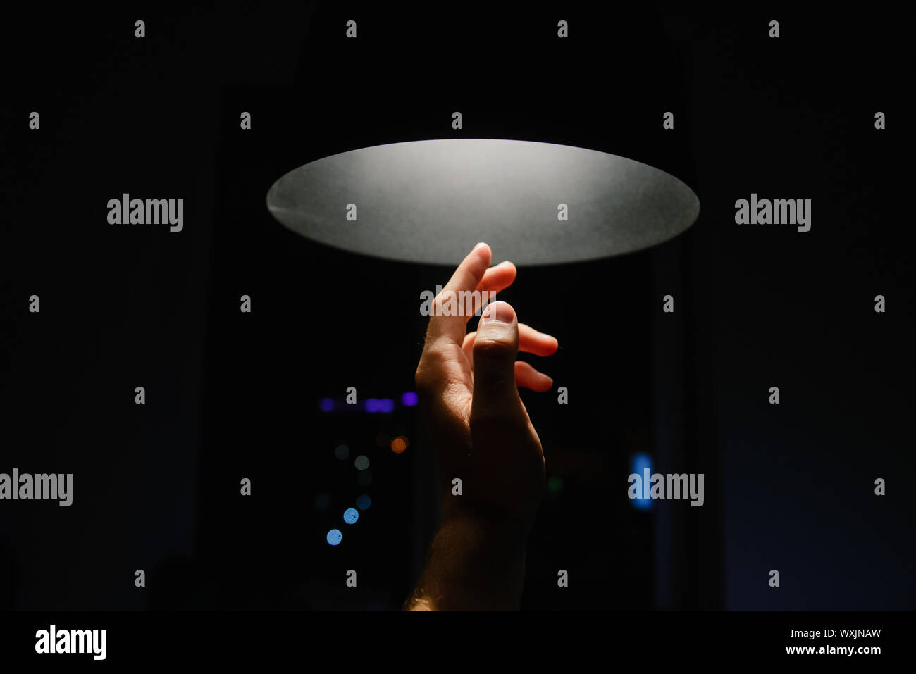 Man's hand reaching towards a ceiling light Stock Photo - Alamy