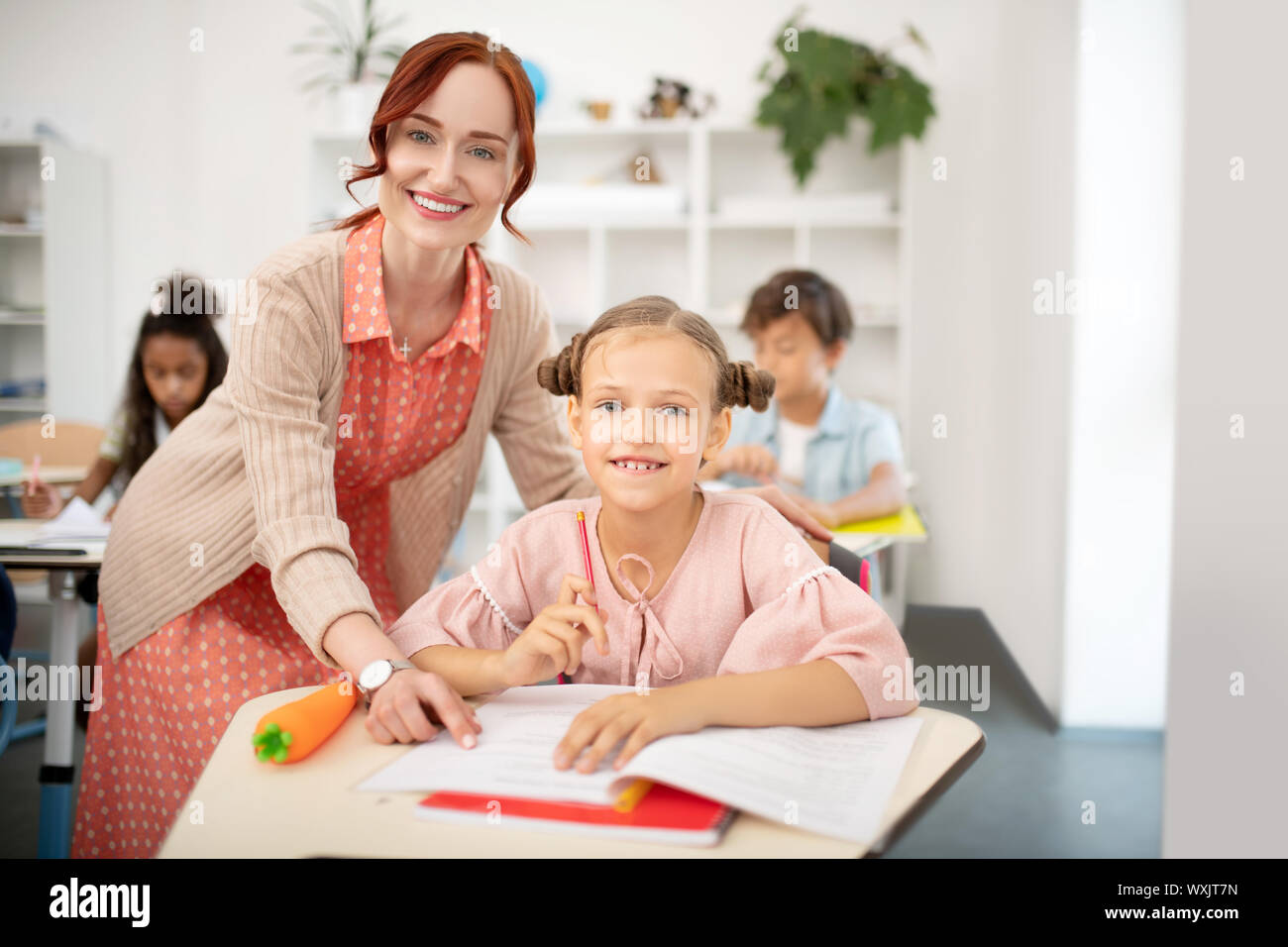 Beautiful king teacher helping girl with task during the lesson Stock ...