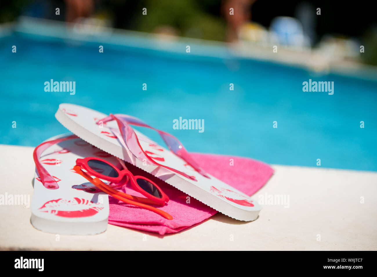 Flip flops near the swimming pool with blue water Stock Photo - Alamy