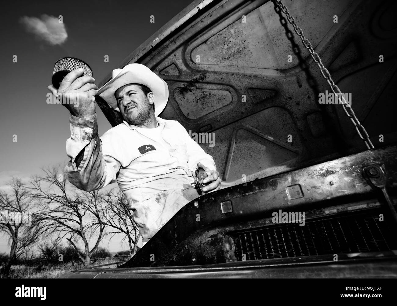 Man in cowboy hat under the hood of truck Stock Photo - Alamy