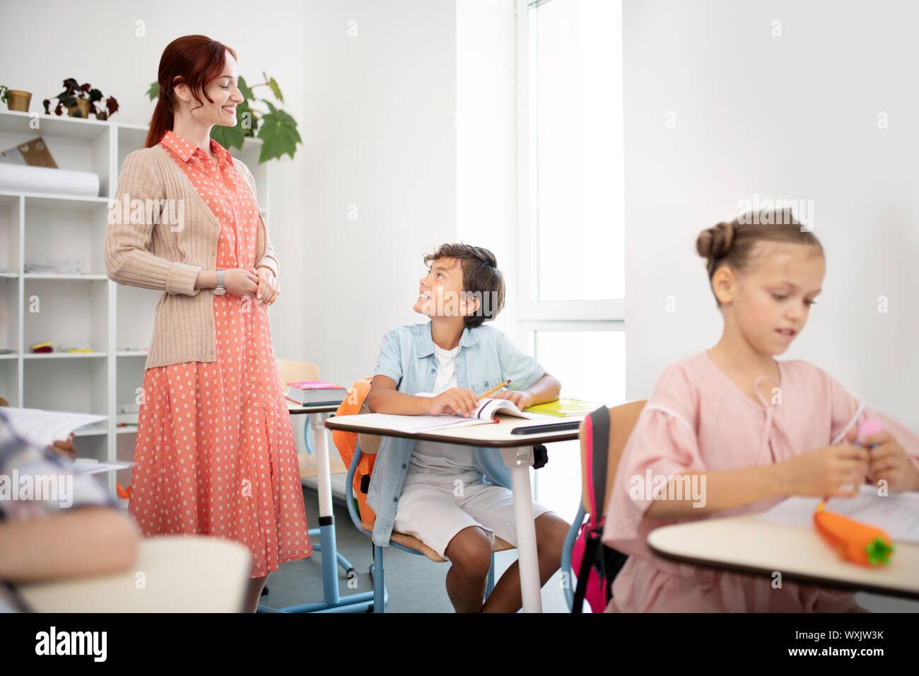 Red-haired teacher answering question of smart dark-haired boy Stock ...